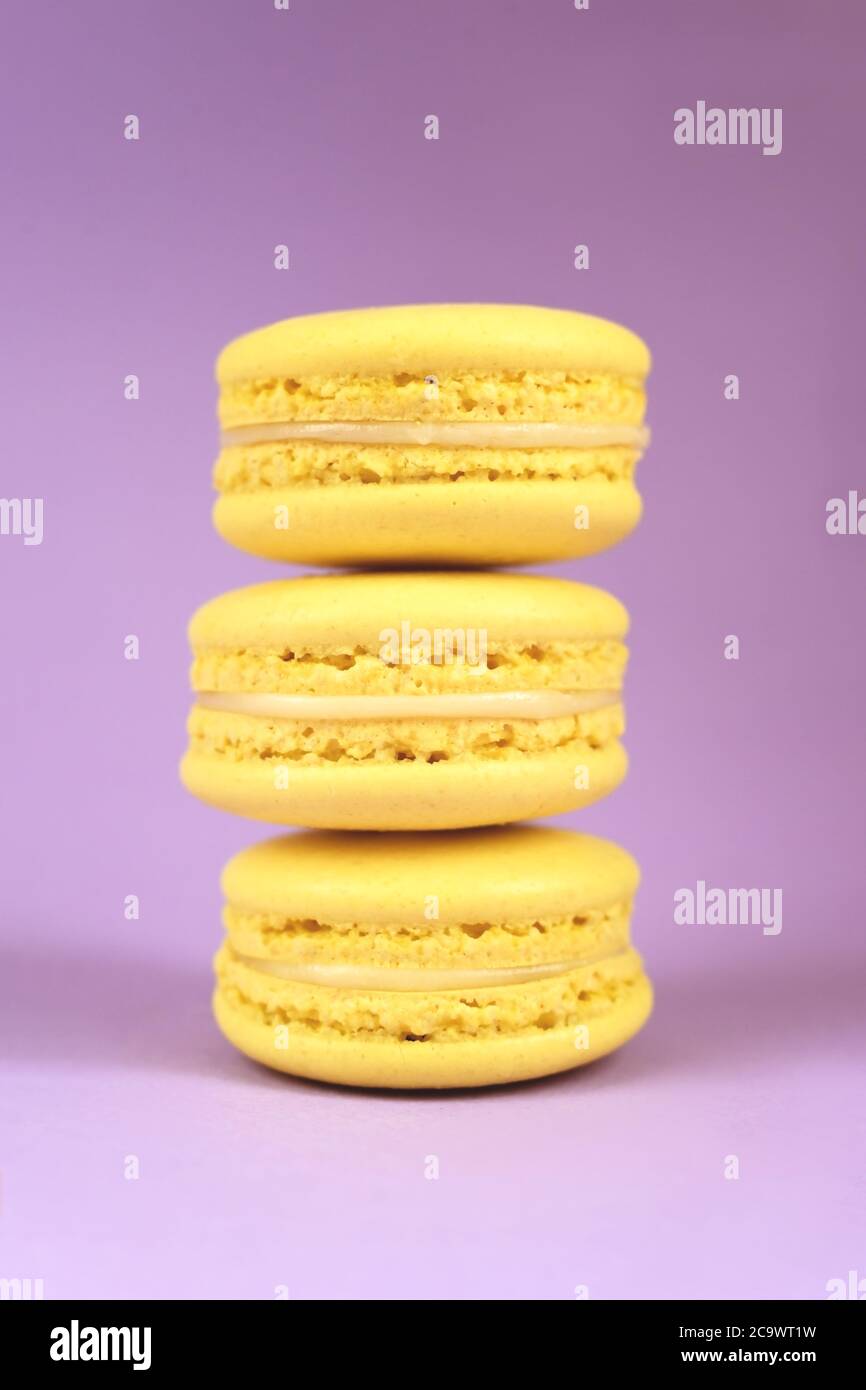 Three tasty french yellow colored macarons on the purple background ...