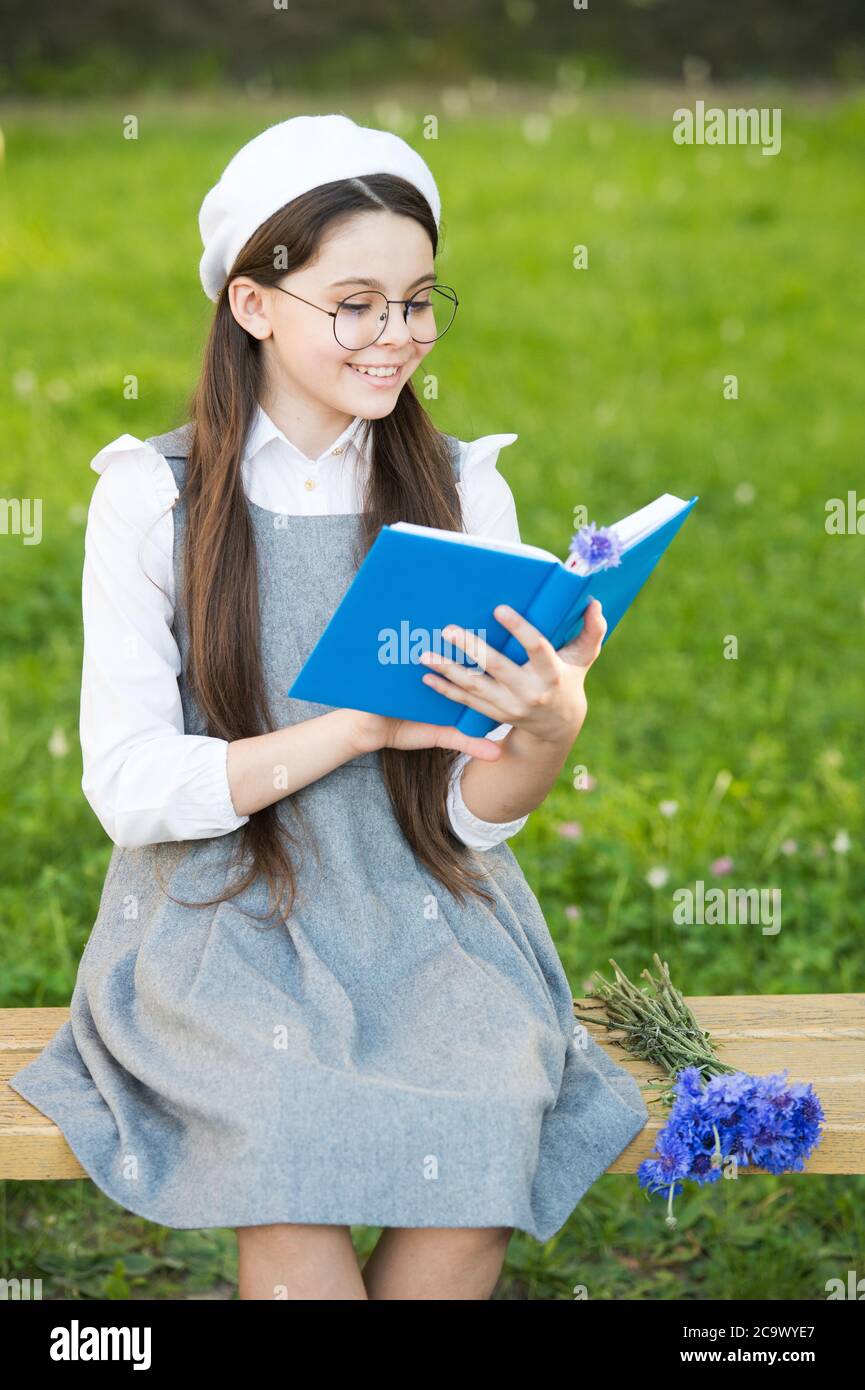 Elegant schoolgirl child girl reading book in park, french language ...