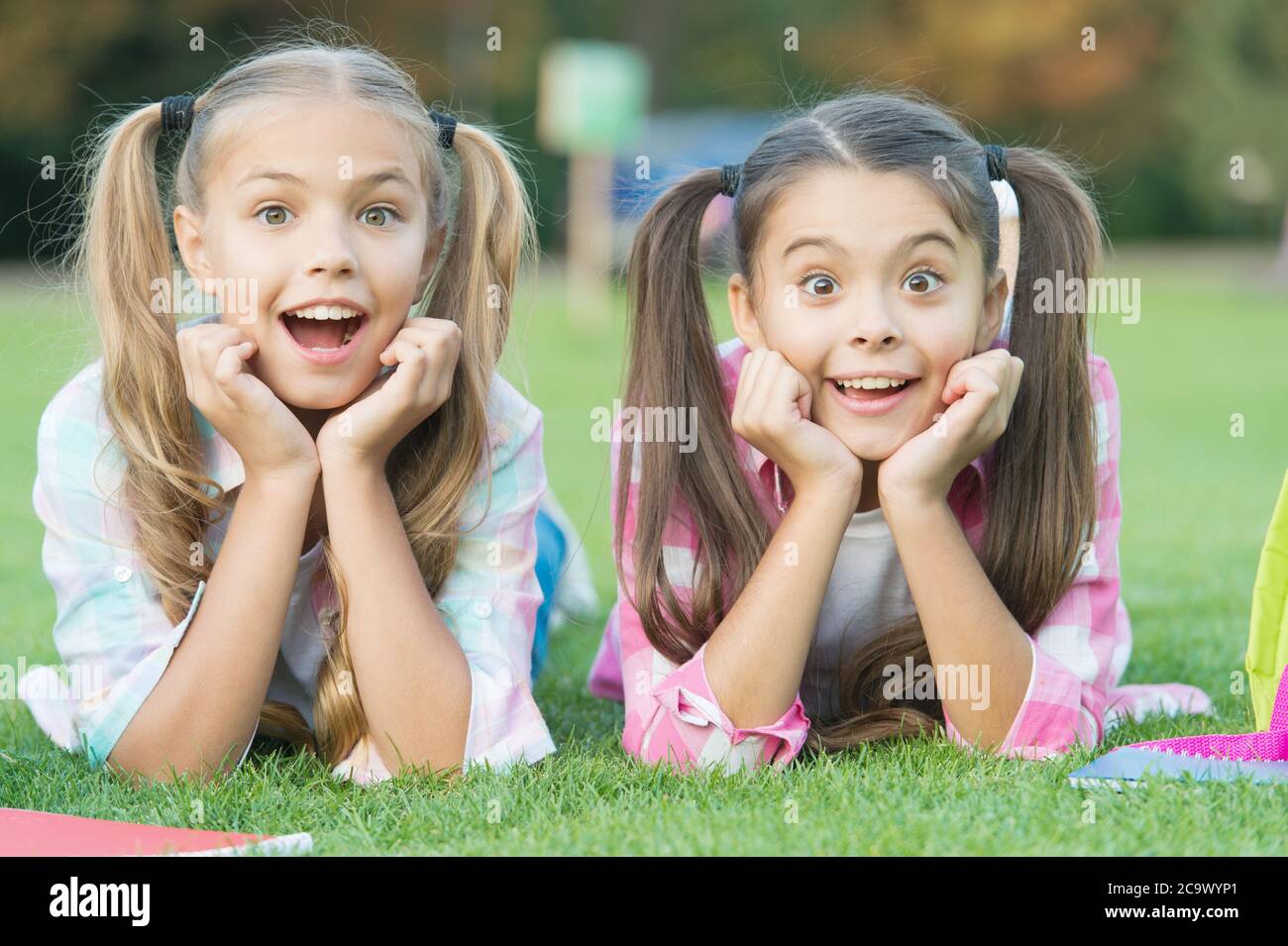 Cute smiling kids sisters relax green grass, real surprise concept ...