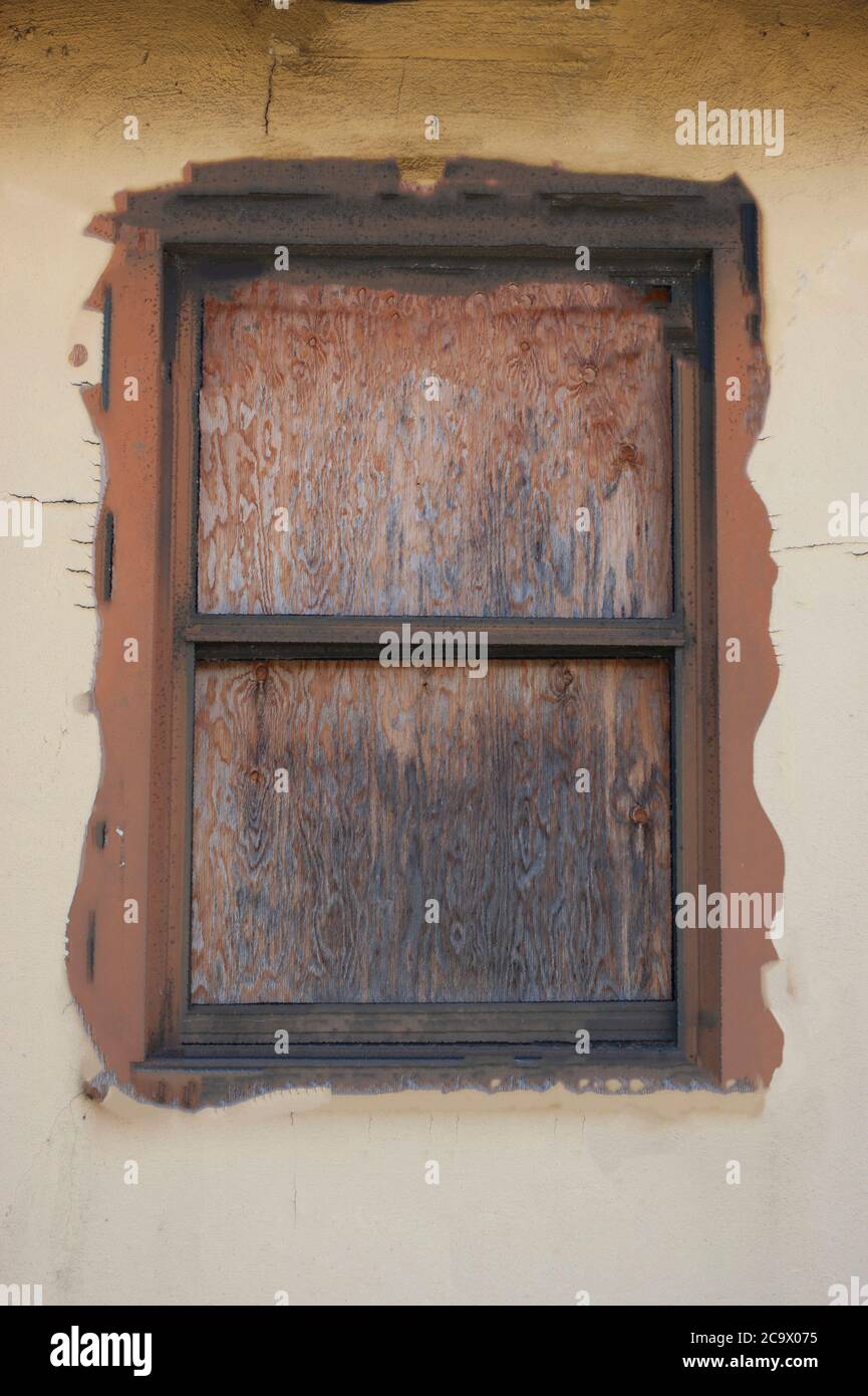 Boarded window with abstract embellished frame and cracked stucco wall ...
