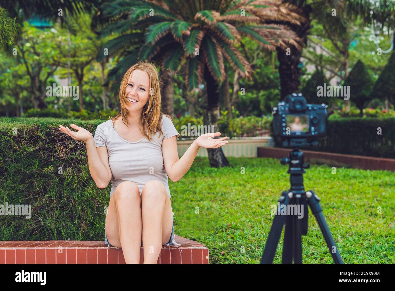 A young female blogger is leading her video blog in front of the camera ...