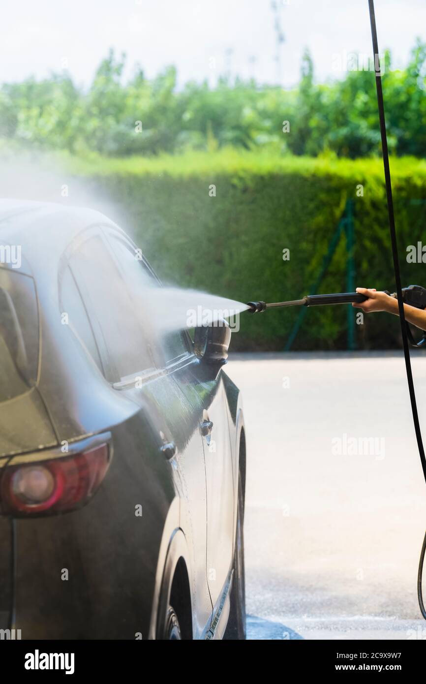 Car's right side being washed with a high pressure water spray wand on ...