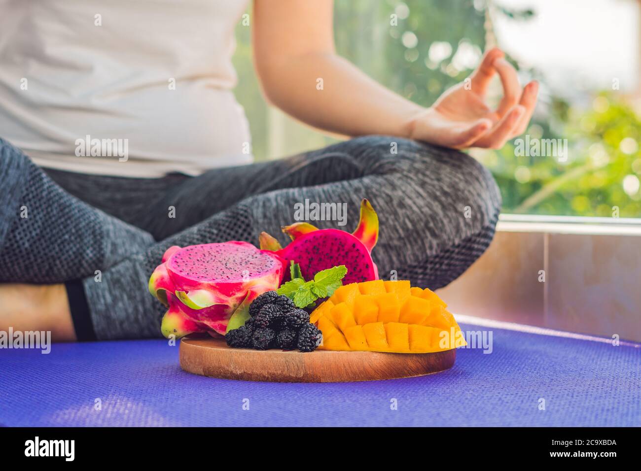 hand of a woman meditating in a yoga pose, sitting in lotus with fruits in front of her dragon ...
