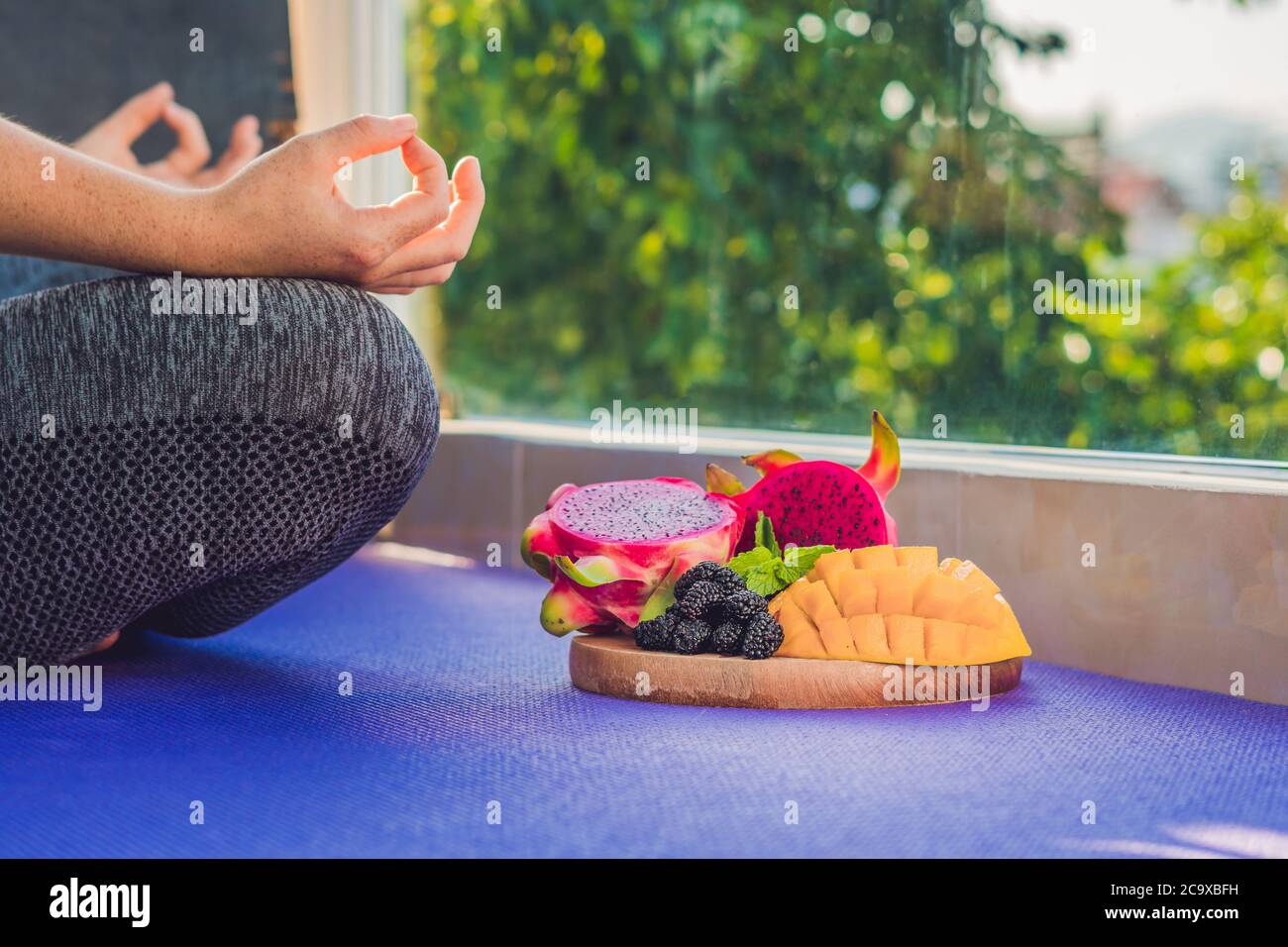hand of a woman meditating in a yoga pose, sitting in lotus with fruits in front of her dragon ...