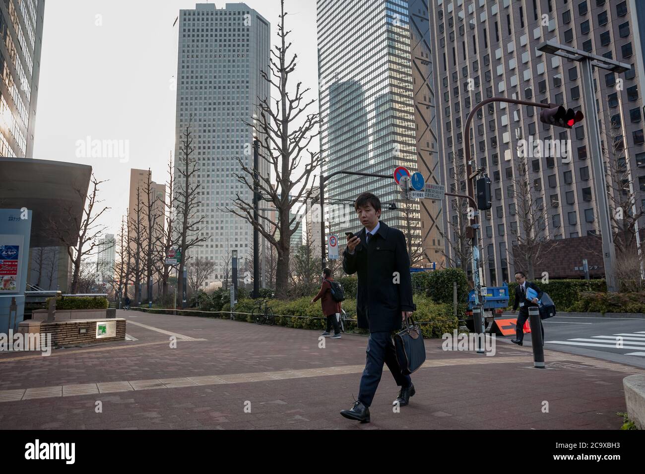 A Japanese office worker or salaryman checks his smartphone while ...