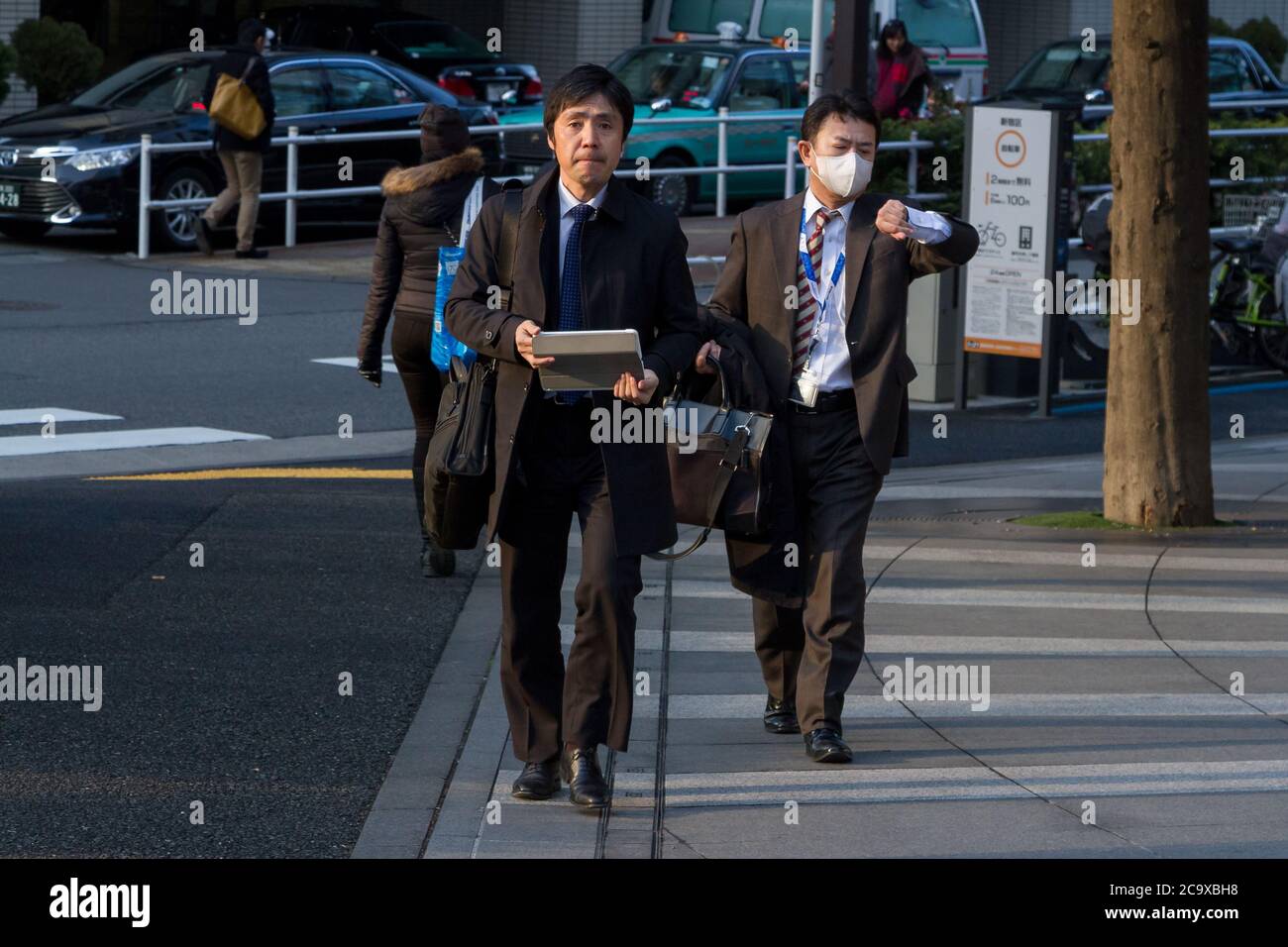 Two Japanese salarymen or male office workers walking in the street in ...