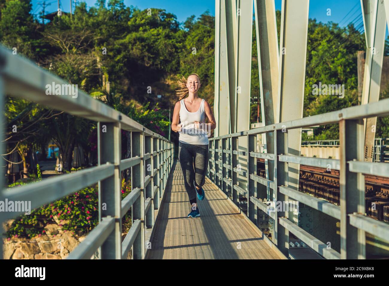 Beautiful woman running over bridge during sunset Stock Photo - Alamy