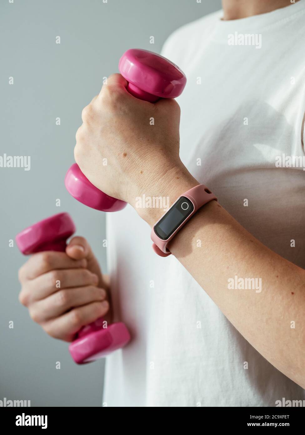 Unrecognizable young woman in white shirt with pink wearable device and ...