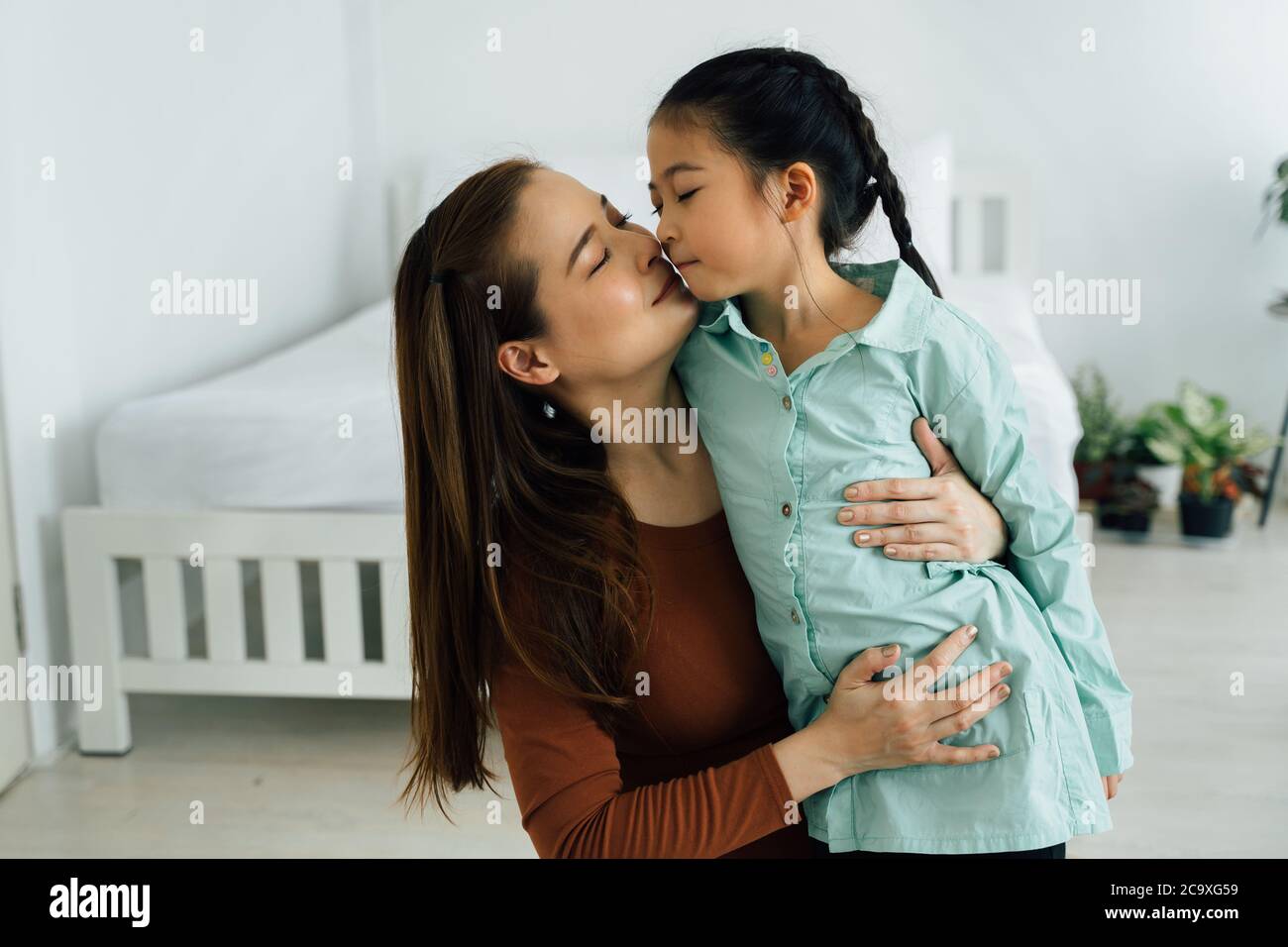 Affectionate Asian mother cuddling cute girl Stock Photo - Alamy