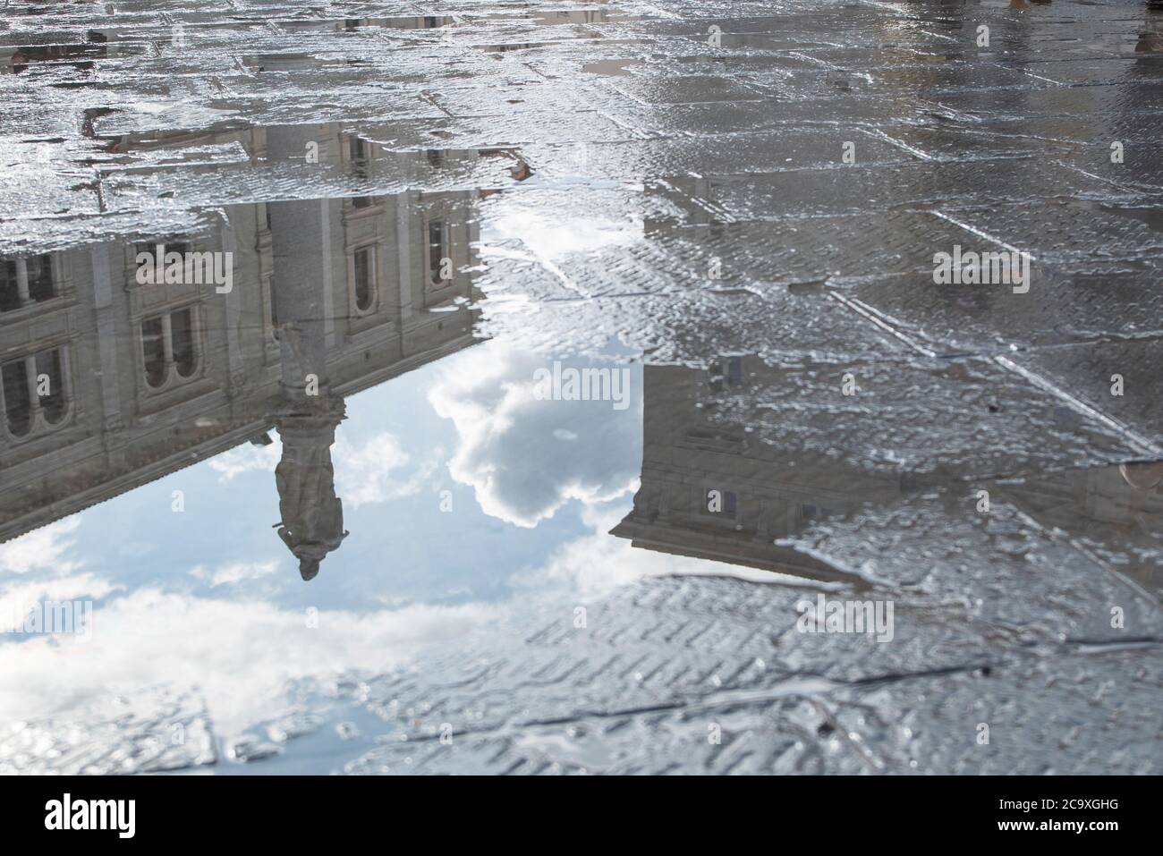 The buildings are reflected in the puddles formed on the street, after ...