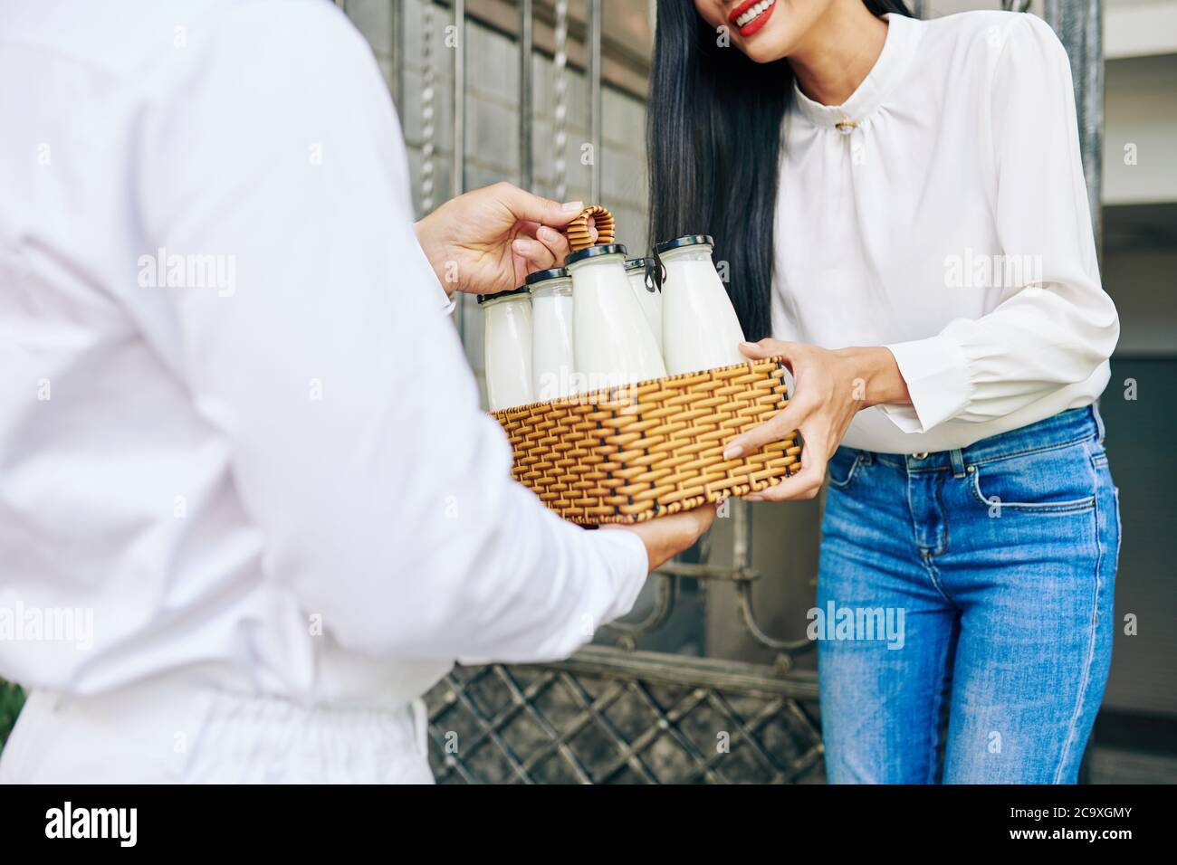 Close-up image of smiling young woman receiving order of fresh milk at ...