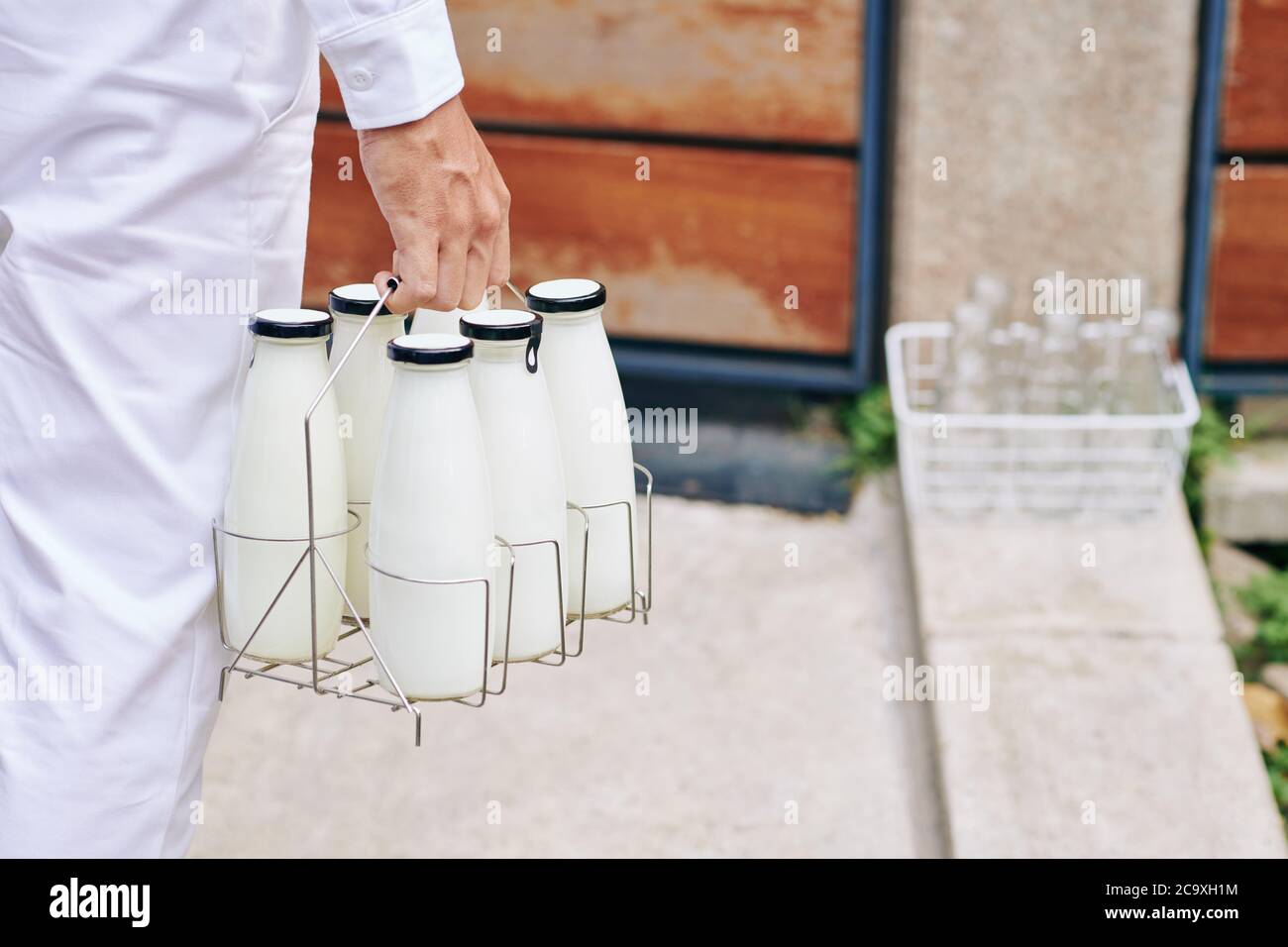 Close-up image of delivery man carrying bottles of fresh milk to ...