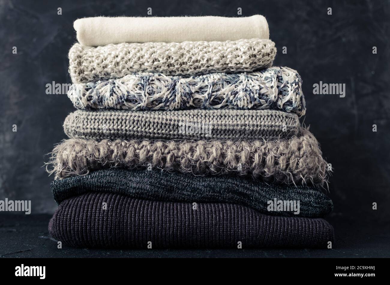 Pile of knitted woolen sweaters. Monochrome gradient shades grey white ...