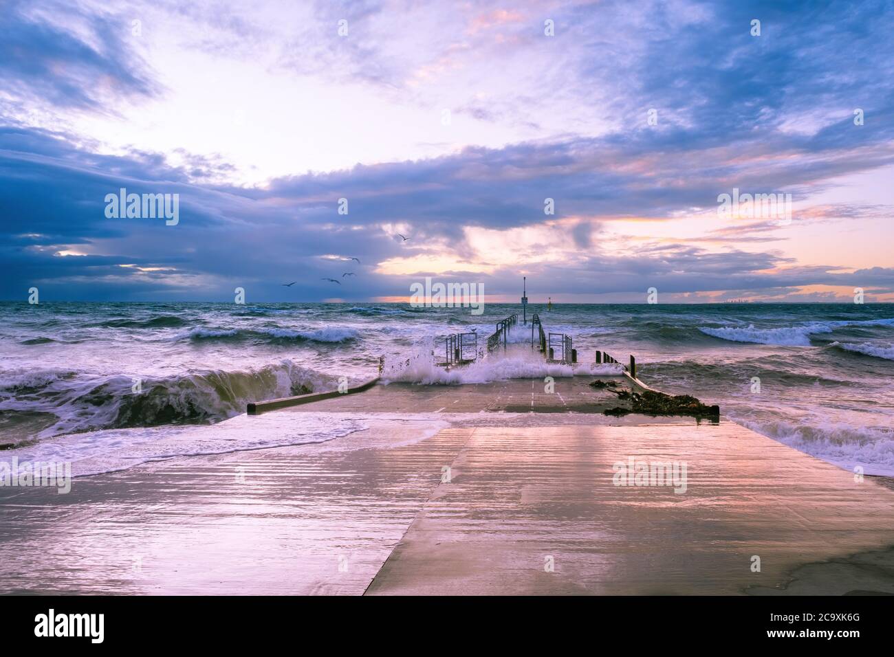 Strong large waves crushing over pier at sunset Stock Photo - Alamy