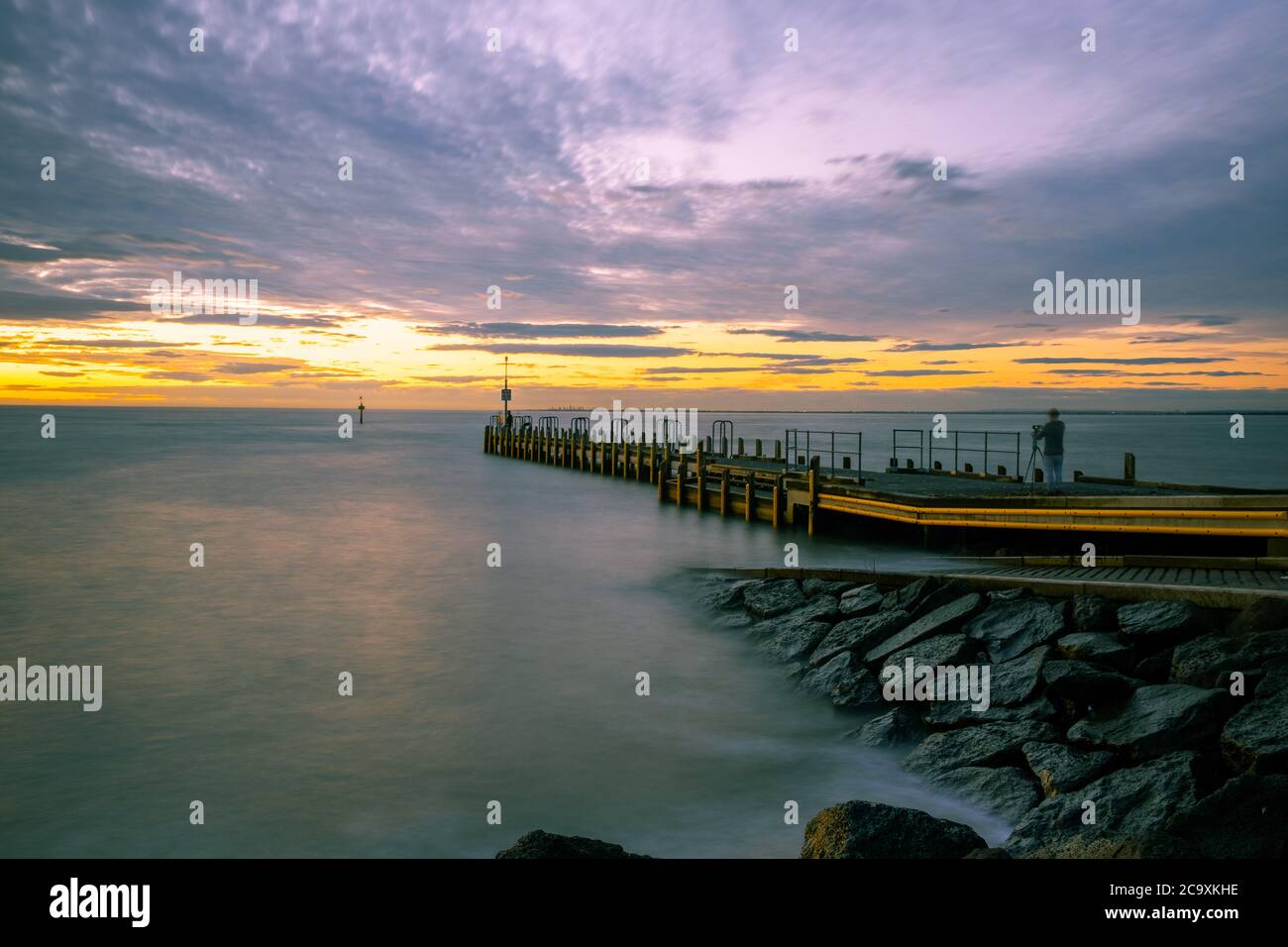Long exposure of silky smooth ocean water and pier at sunset with ...