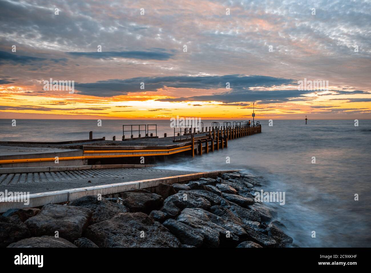 Small pier extending into silky smooth ocean at sunset - long exposure ...