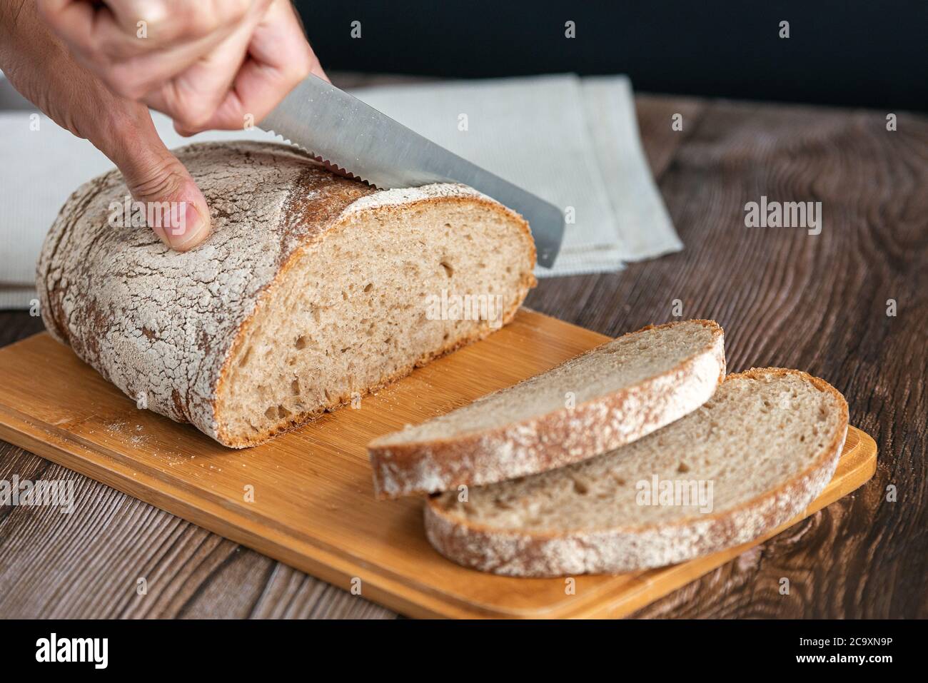 Close up of hands cutting a slice of bread. Male hands cutting bread on ...