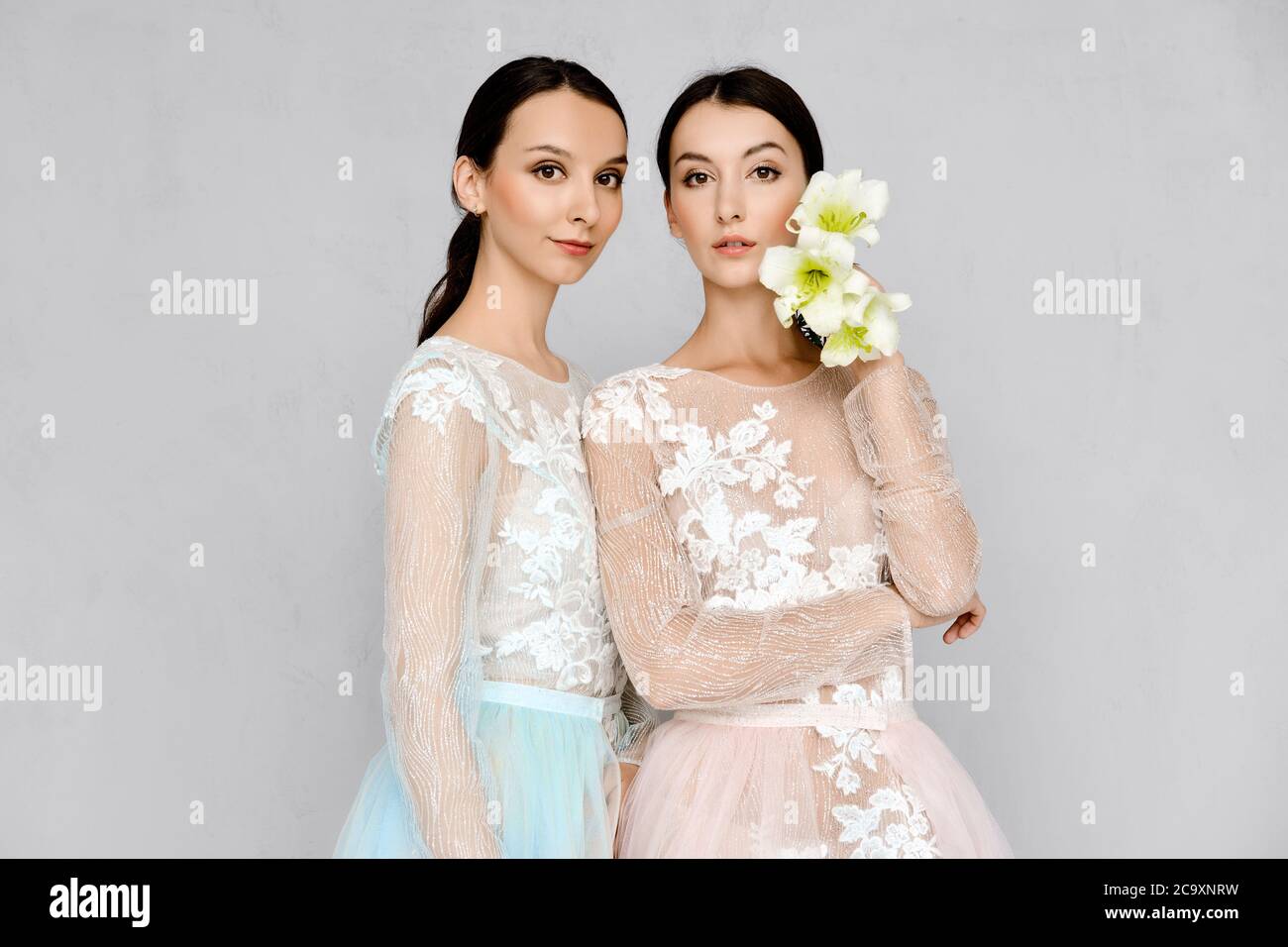 Two beautiful young women in transparent tulle dresses with lace posing ...