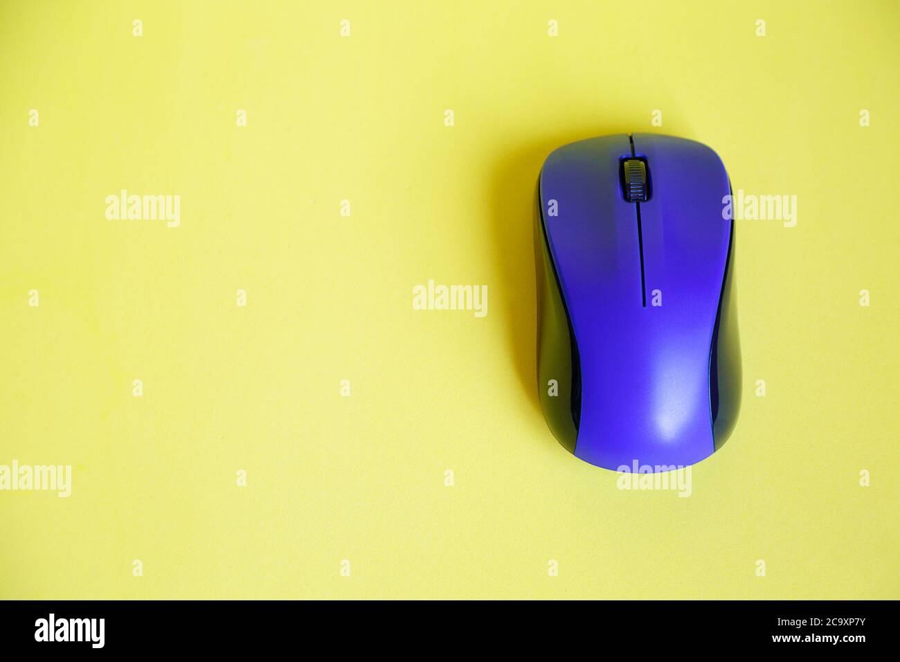 Top view of a blue wireless mouse on yellow background, with copy space ...