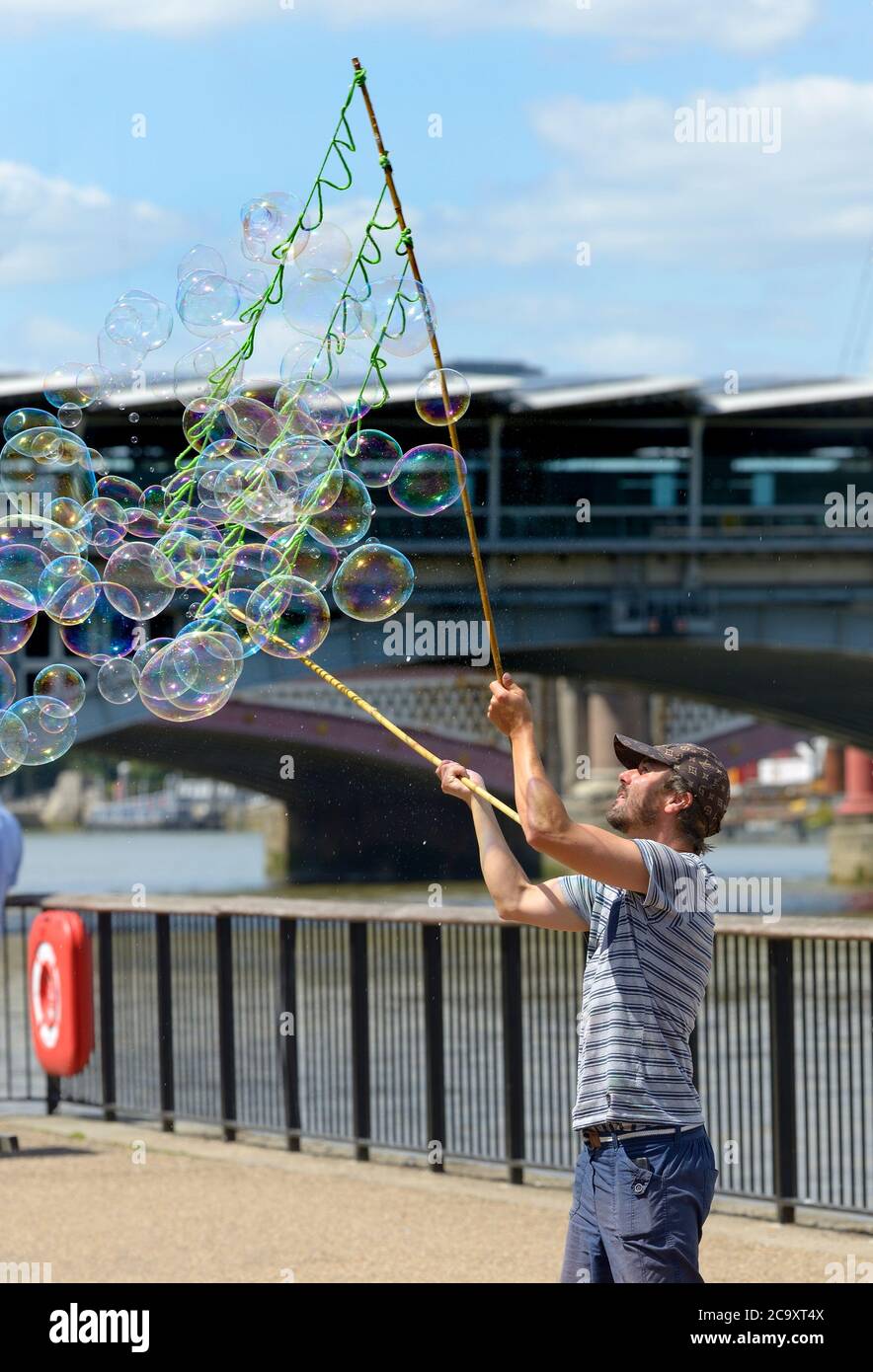 London, England, UK. Street entertainer on the South Bank blowing ...