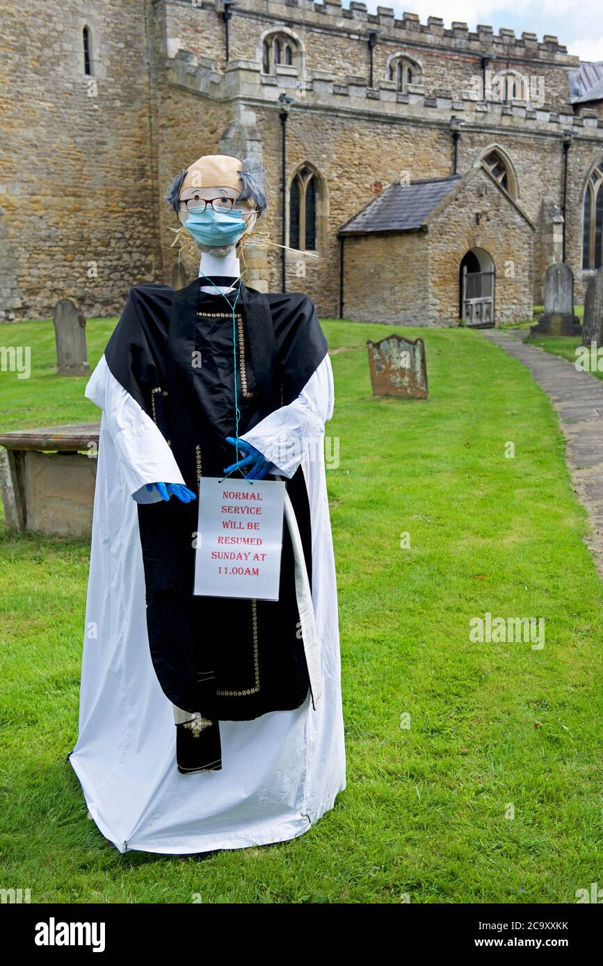 Scarecrow vicar in the churchyard of All Saints Church in the village ...