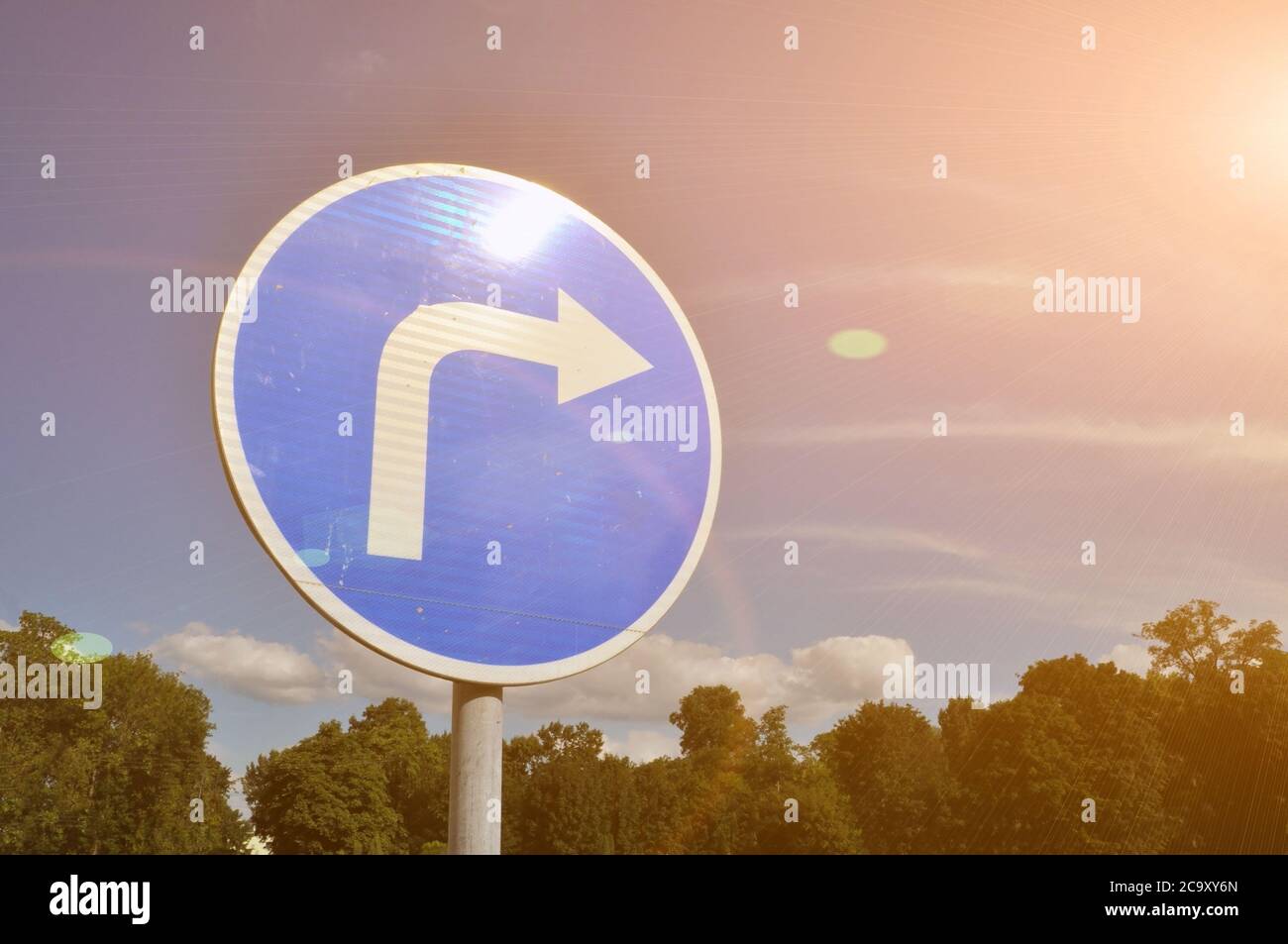 Road sign showing right turn against blue sky Stock Photo - Alamy