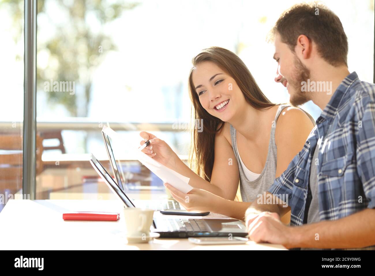 Happy students with laptops check document sitting on a coffee shop ...