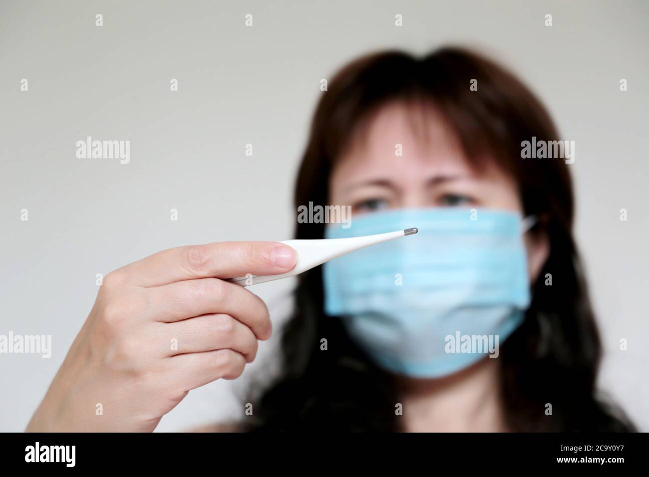 Coronavirus symptoms, woman in medical face mask measures body ...