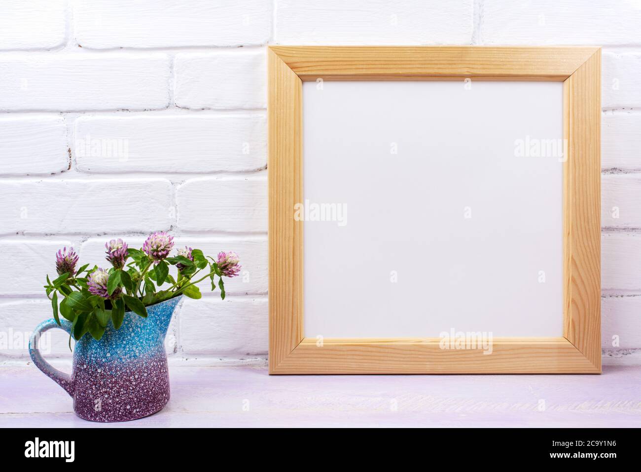 Wooden square picture frame mockup with pink clover in the blue pitcher ...