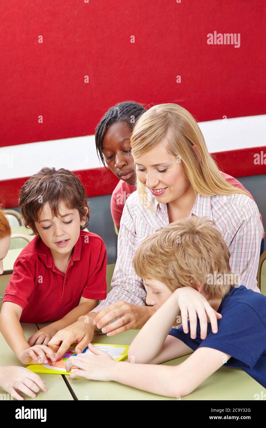 Students solve a puzzle together with the teacher at school Stock Photo ...