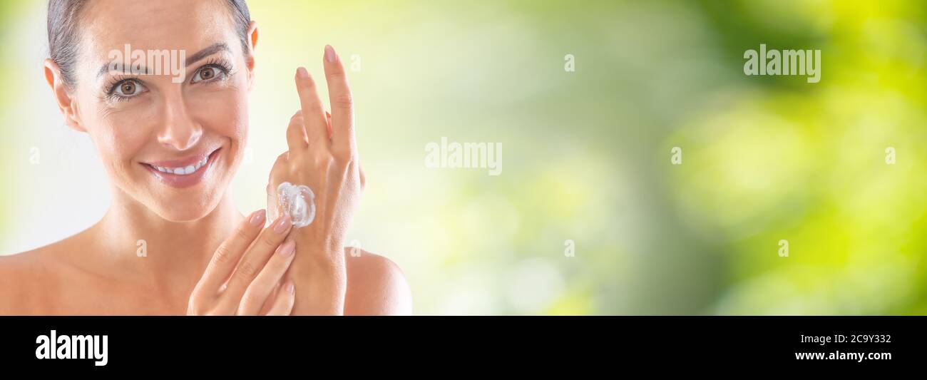 Beautiful young woman applying cream to her hand. Skincare spa wellness ...