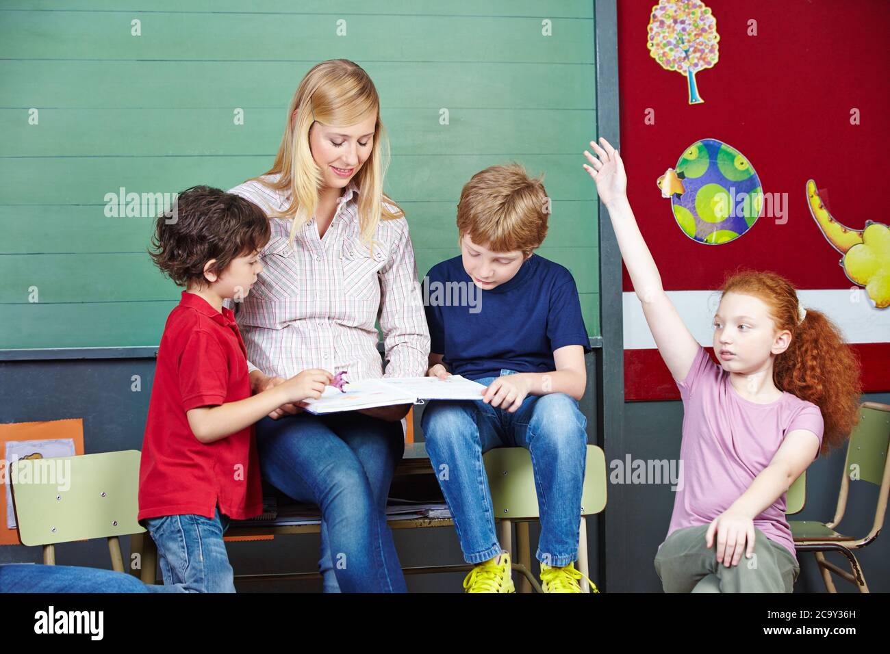 Teachers and students read a book at school Stock Photo - Alamy