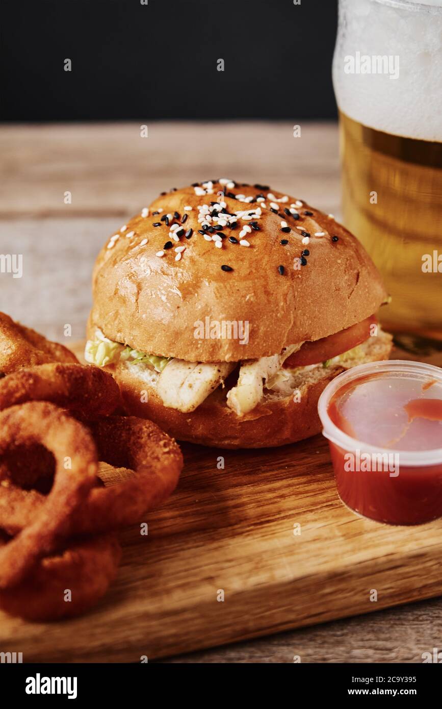 Different types of fastfood and snacks and glass of beer on table ...
