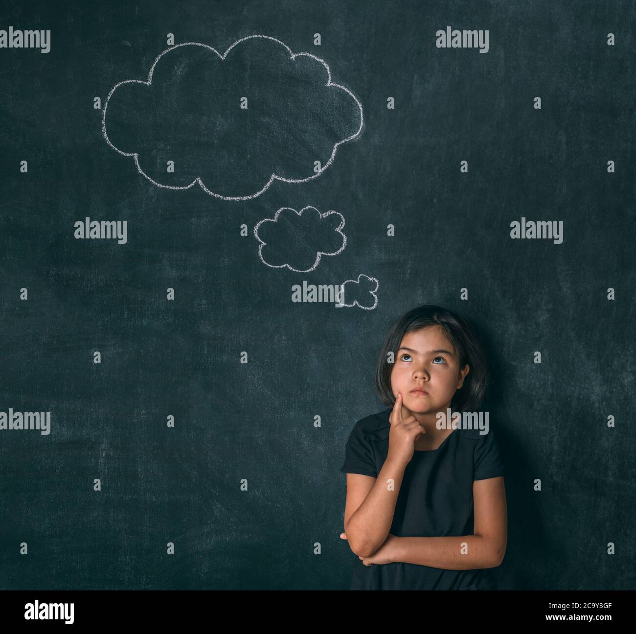 Back to school. Serious little girl thinking touching her head with a ...