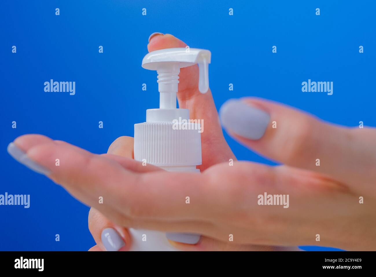 Woman pushing dispenser, squeezing out antiseptic gel on palm, cleaning ...