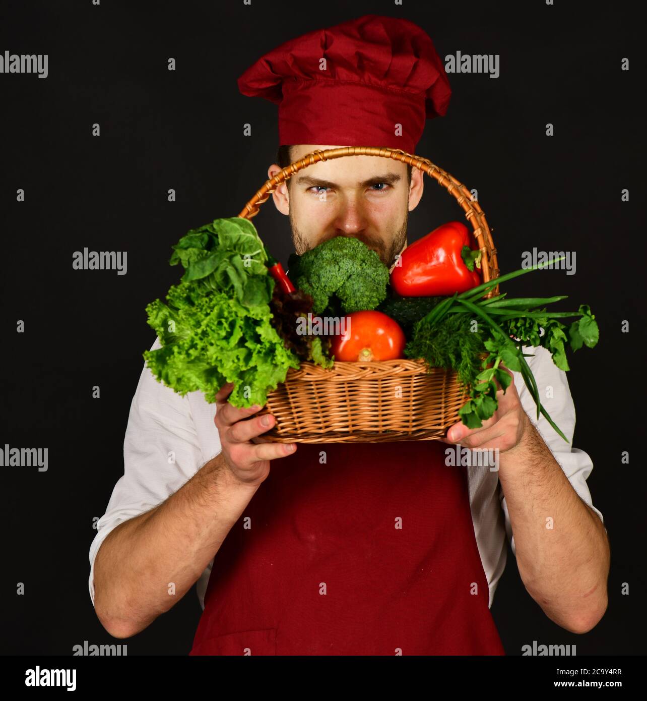 Cook with strict face holds veggies in basket. Man with vegetables on ...