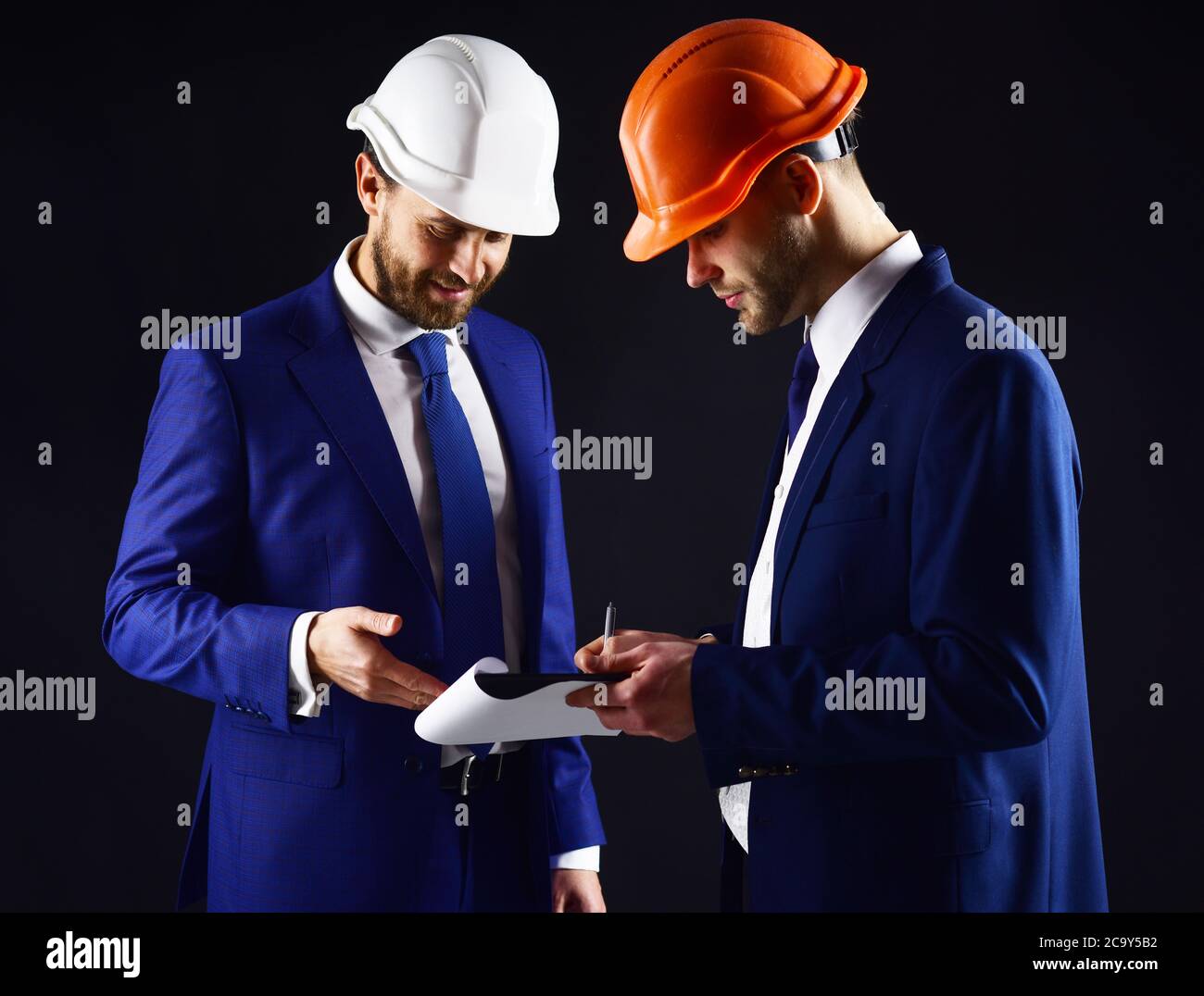 Engineers with smiling faces look at project. Businessman and architect ...