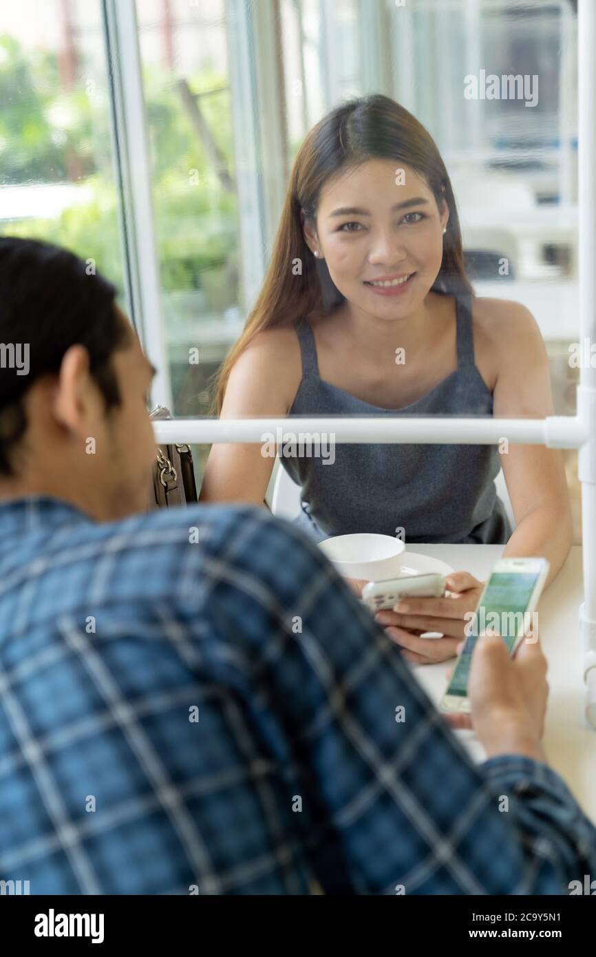 Asian young couple eating out together at new normal social distance ...