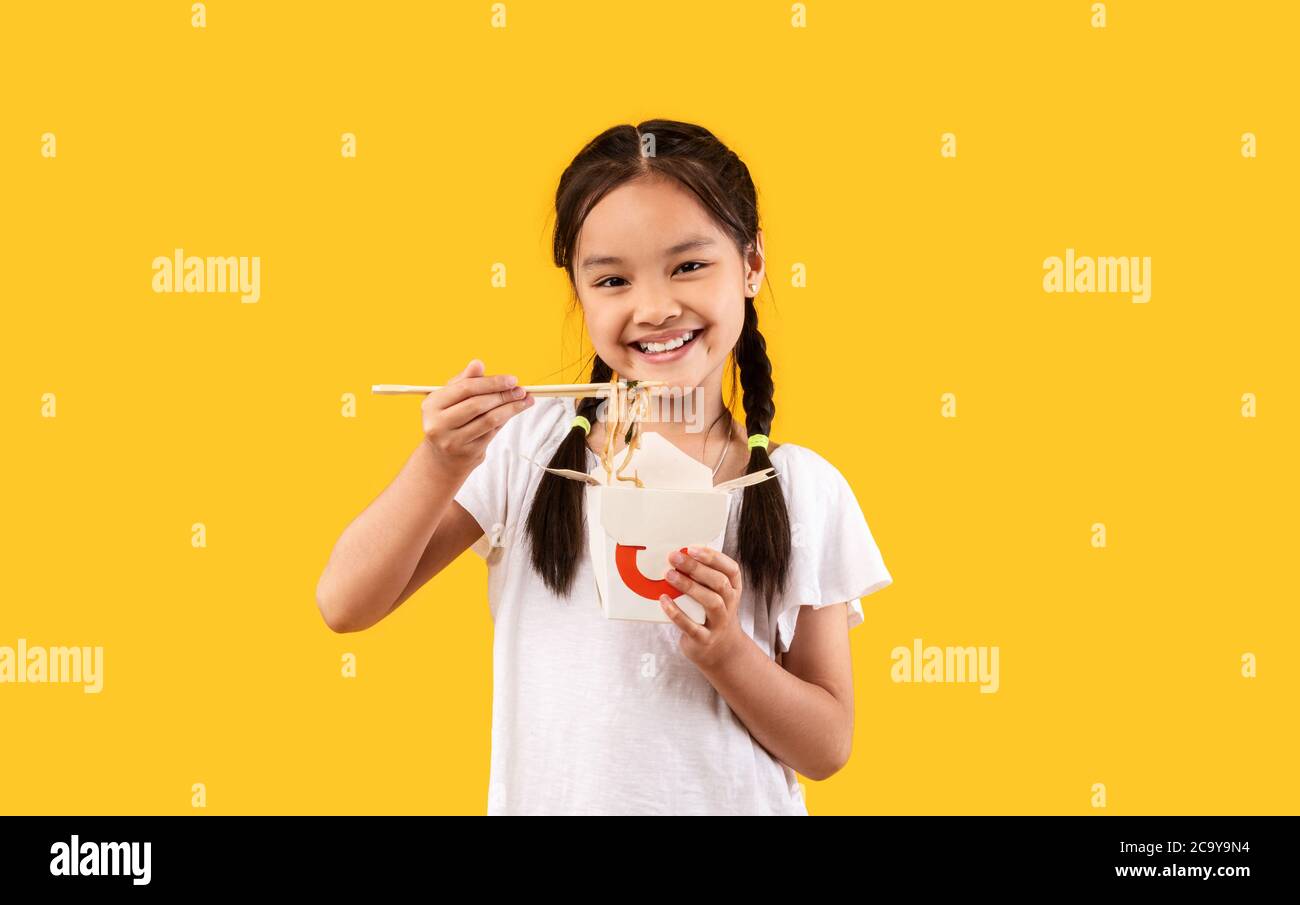 Asian Girl Eating Noodles From Box Using Chopsticks, Studio Shot Stock ...