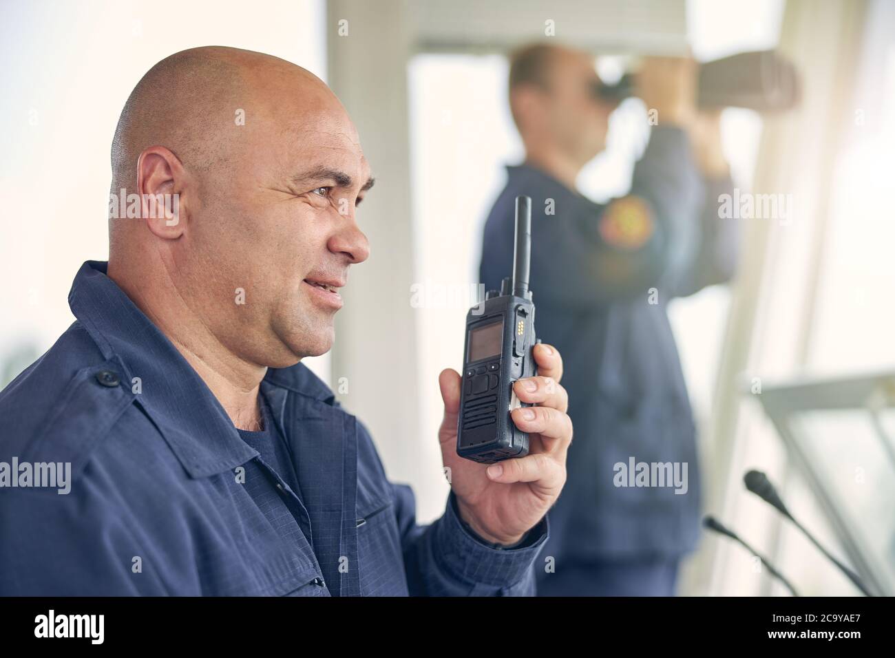 Smiling handsome worker holding walkie talkie in hand Stock Photo - Alamy