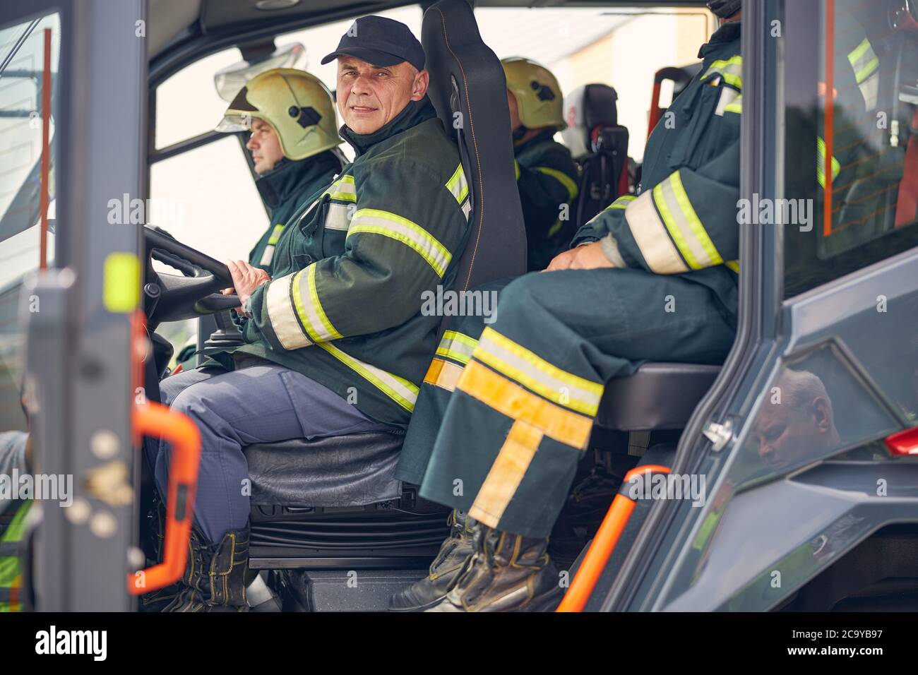 Senior man sitting in the fire truck with group of firefighter Stock ...