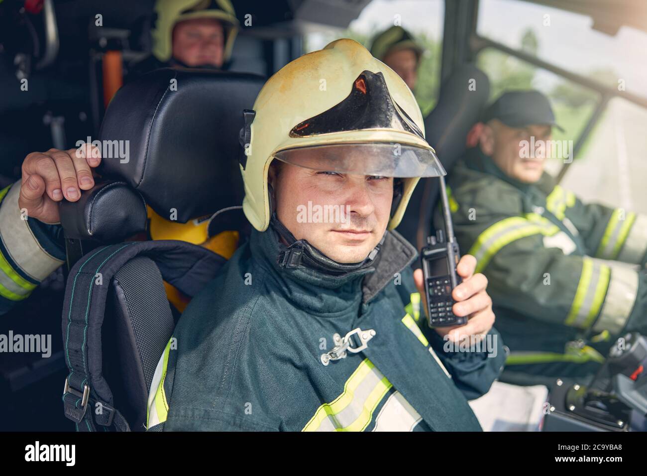 Man in the helmet and work uniform sitting in the fire engine machine ...