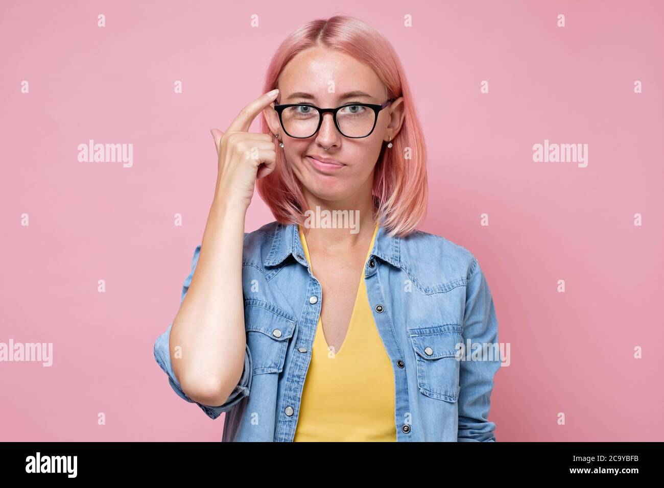 caucasian woman with pink dyed hair thinking trying to solve a problem ...