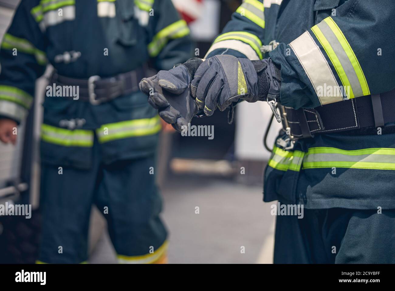 Portrait of strong hands of firefighter standing in front of another ...