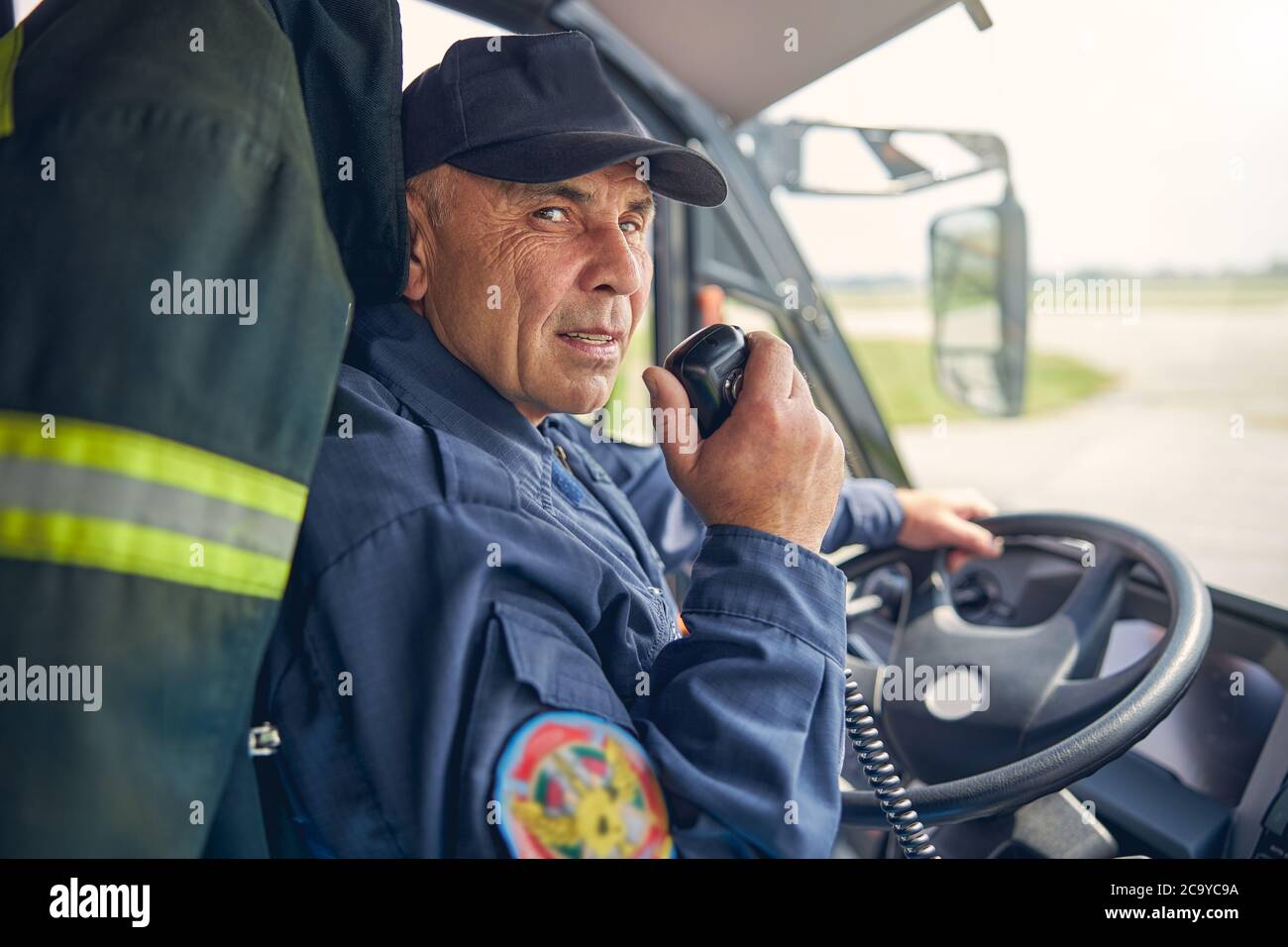 Adult handsome man with walkie talkie in hand sitting in the fire ...