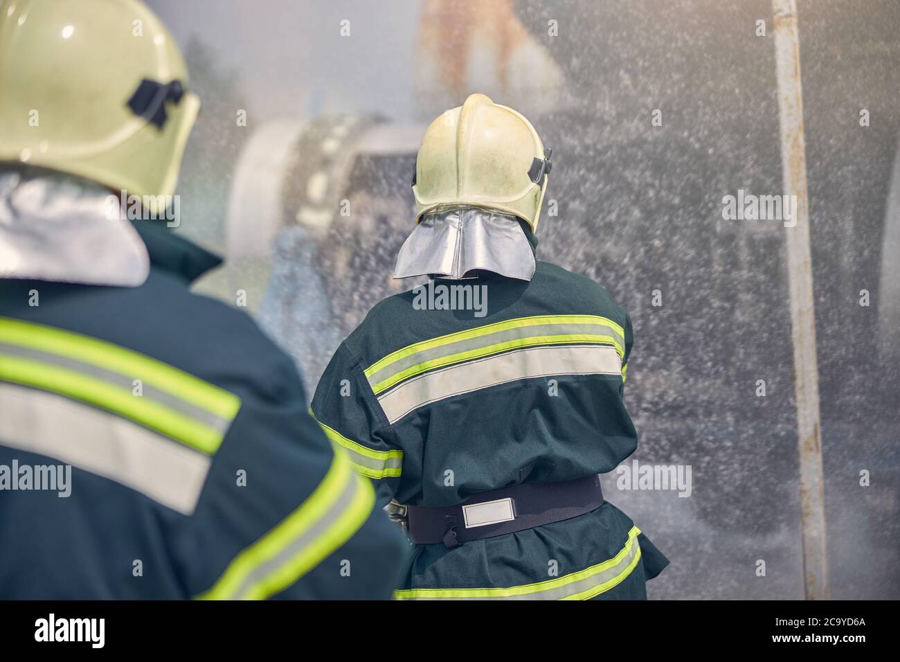 Two firemen wearing fireproof uniform standing next to a emergency ...