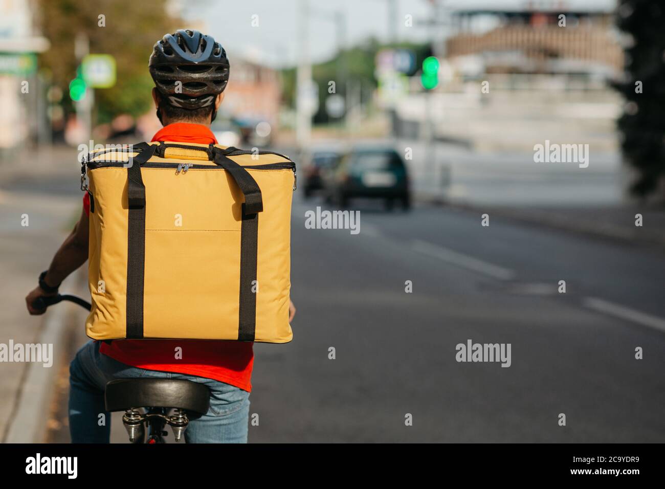 City traffic and bicycle delivery service. Courier in helmet, bag ...