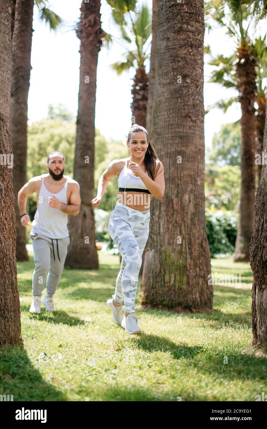 Athletic couple running together. Sport runners jogging on park trail ...