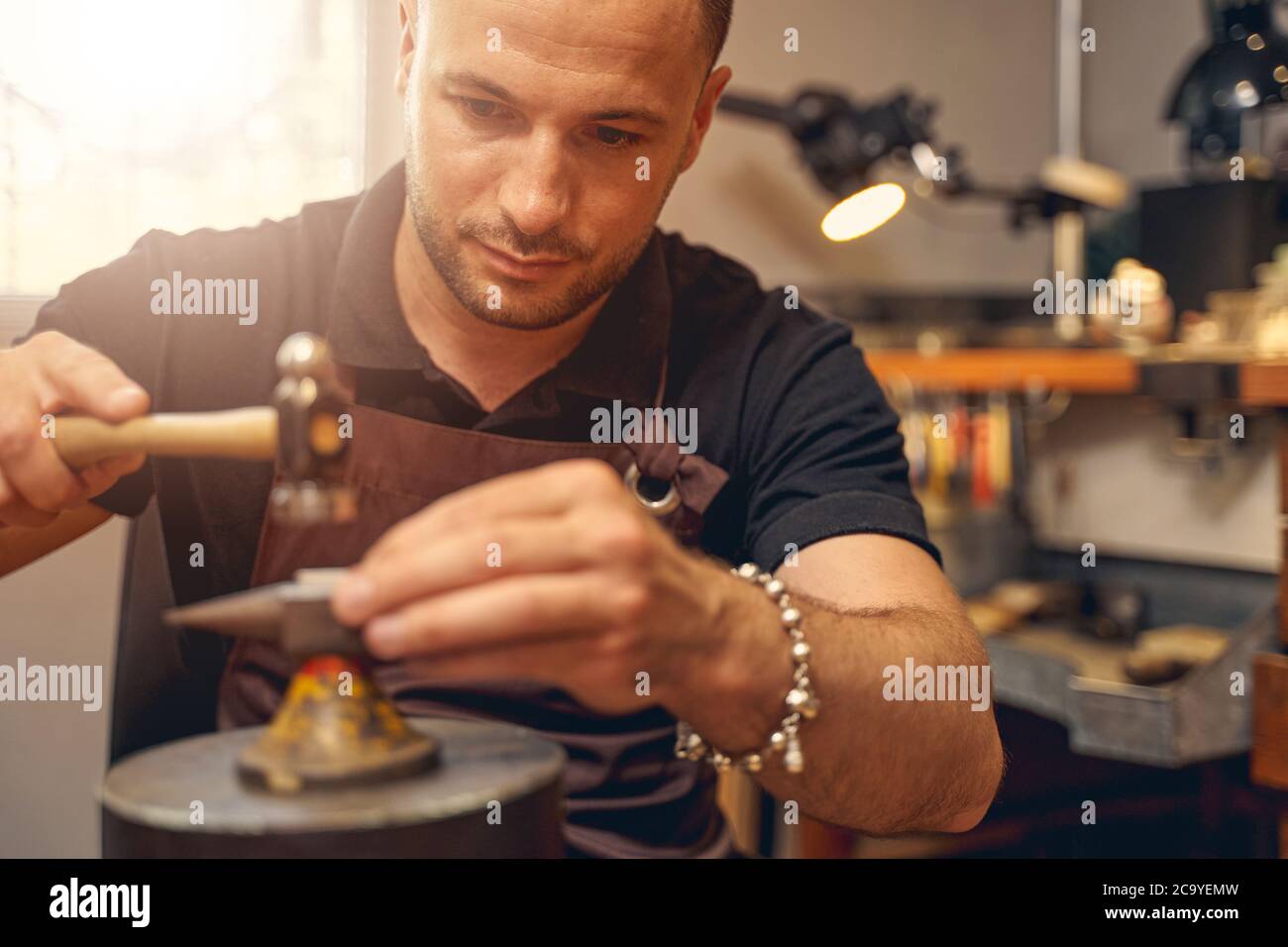 Serious metalsmith treating a workpiece placed on the anvil Stock Photo ...
