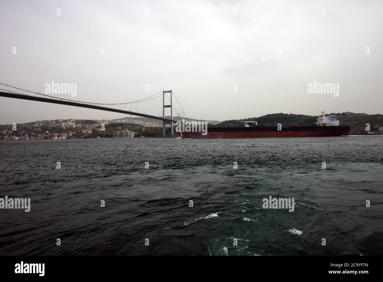 A big oil tanker passing under the bridge in the Bosphorus. The ...